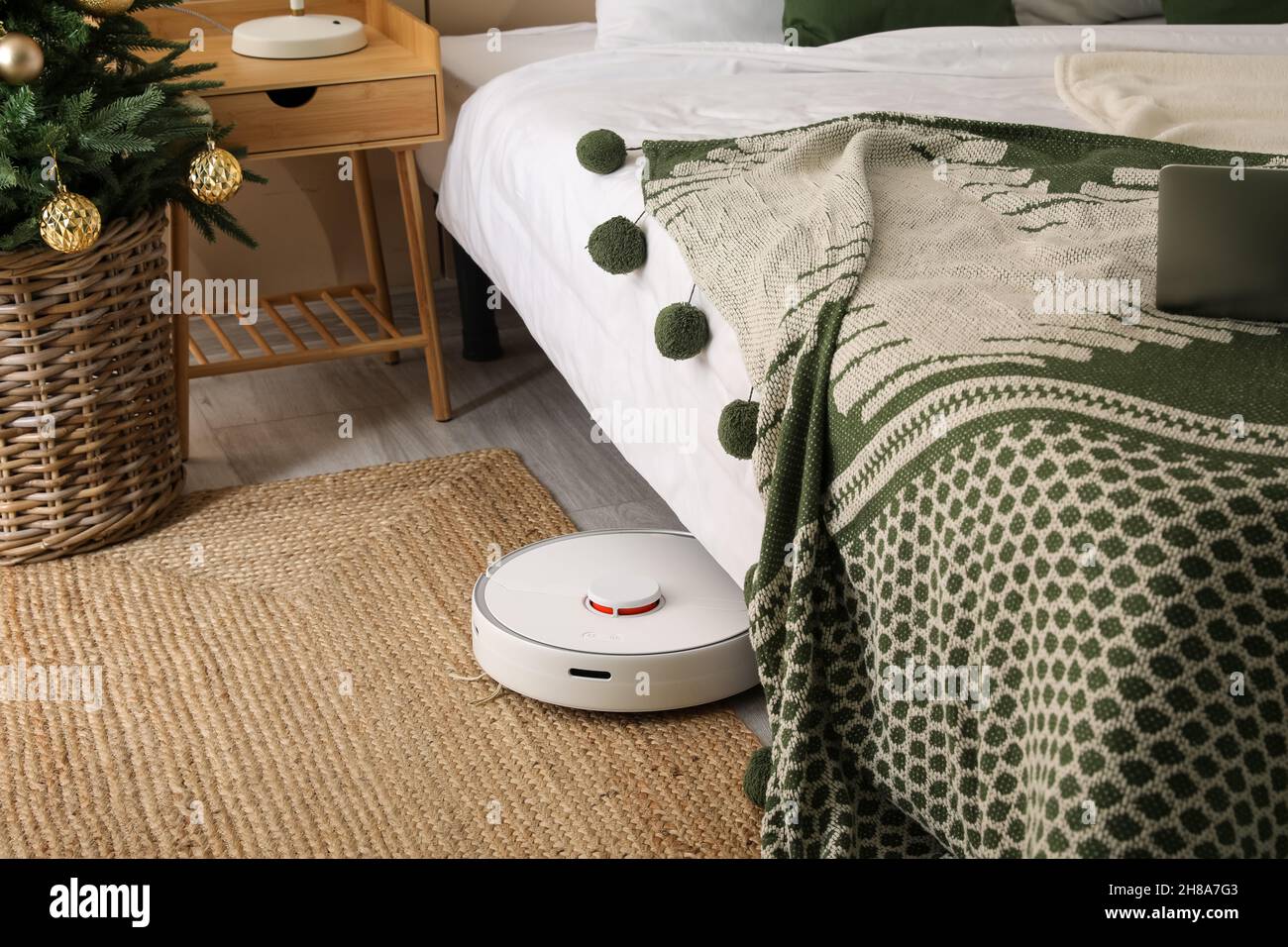 Modern robot vacuum cleaner near bed in room Stock Photo - Alamy