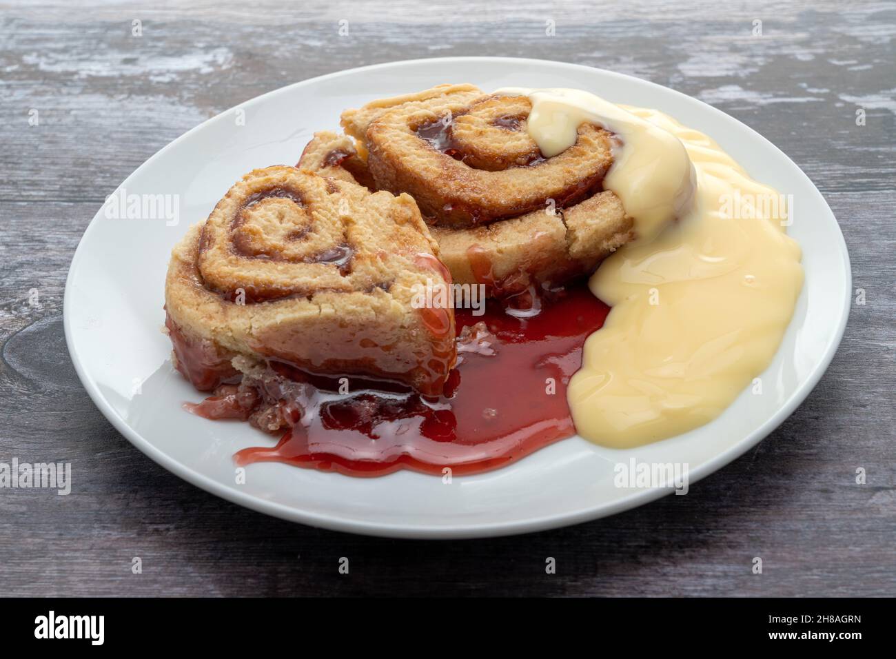 Hot jam roly poly and custard dessert Stock Photo - Alamy
