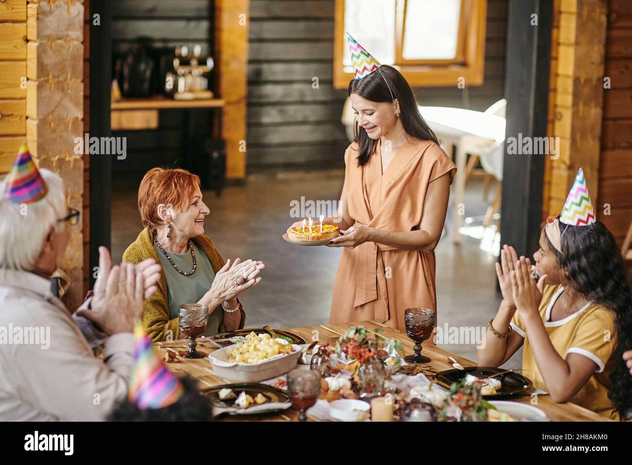 Happy family clapping hands while young smiling woman carrying birthday ...