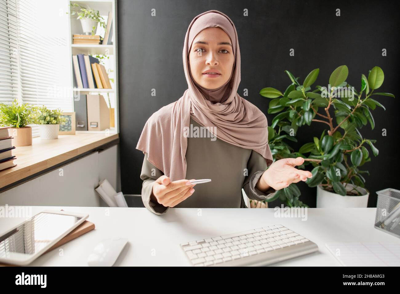 Young confident woman in hijab explaining subject to student while ...