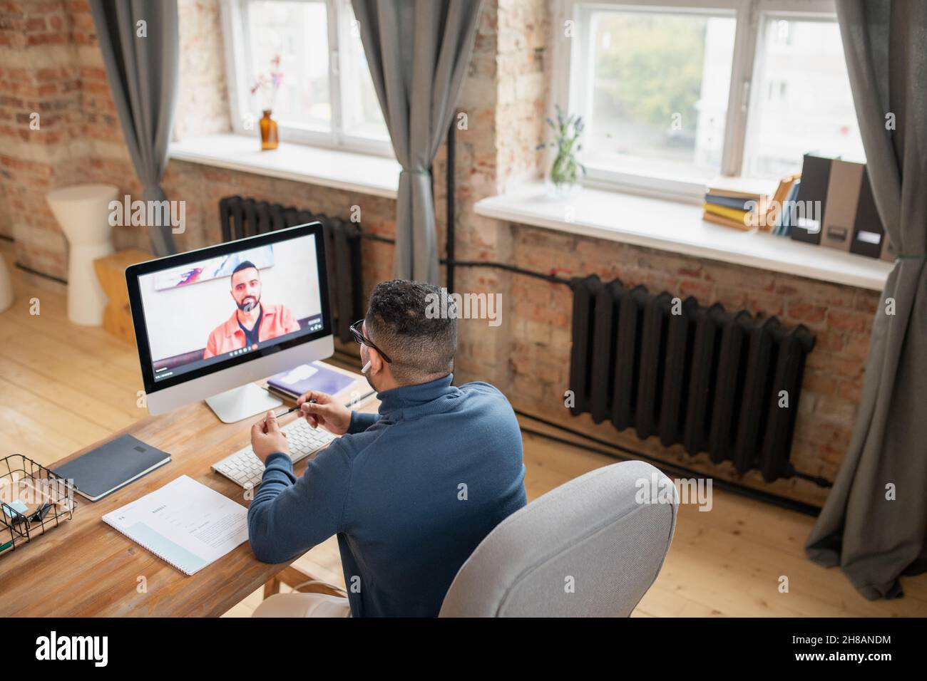 Mature man sitting in front of computer monitor and communicating to ...