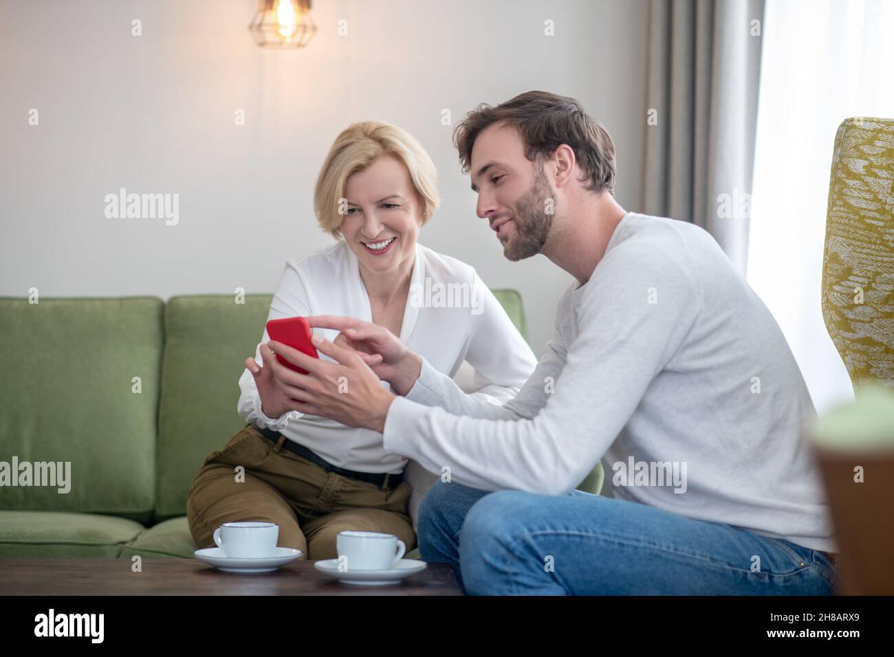 Young man showing photos on his smatphone to his mom Stock Photo - Alamy