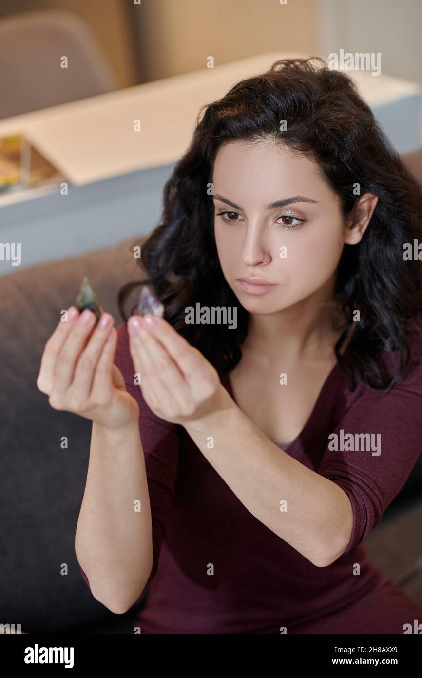 Concentrated woman assessing the quality of minerals in her hands Stock ...