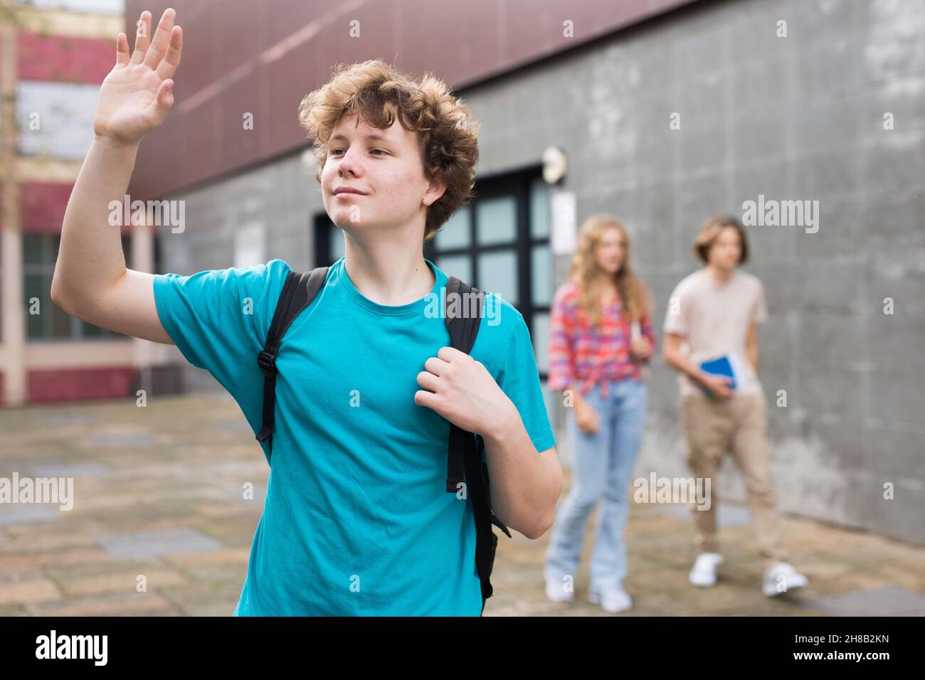 Positive school boy waving hand somebody Stock Photo - Alamy