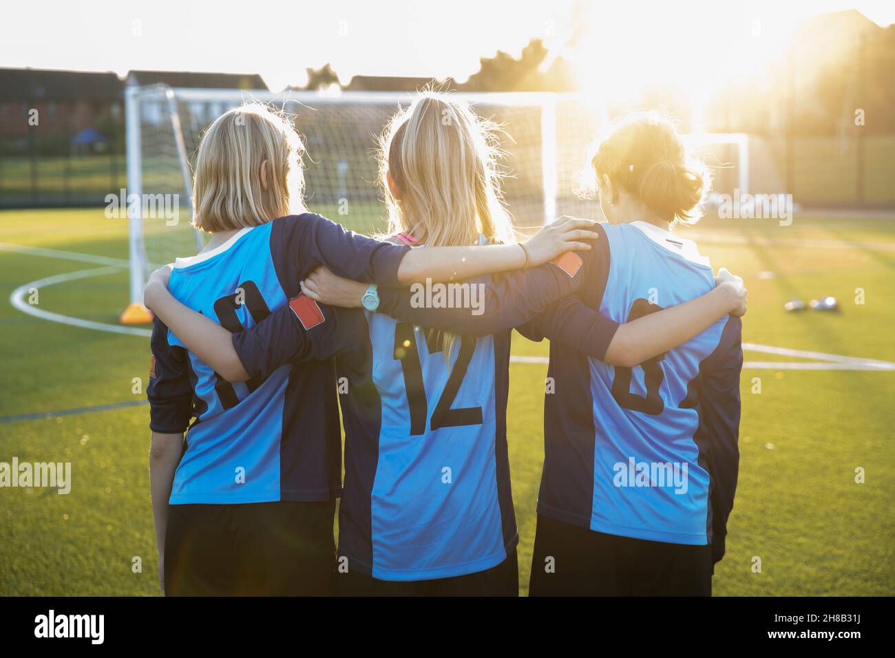 UK, Rear view of female soccer players embracing in field Stock Photo ...