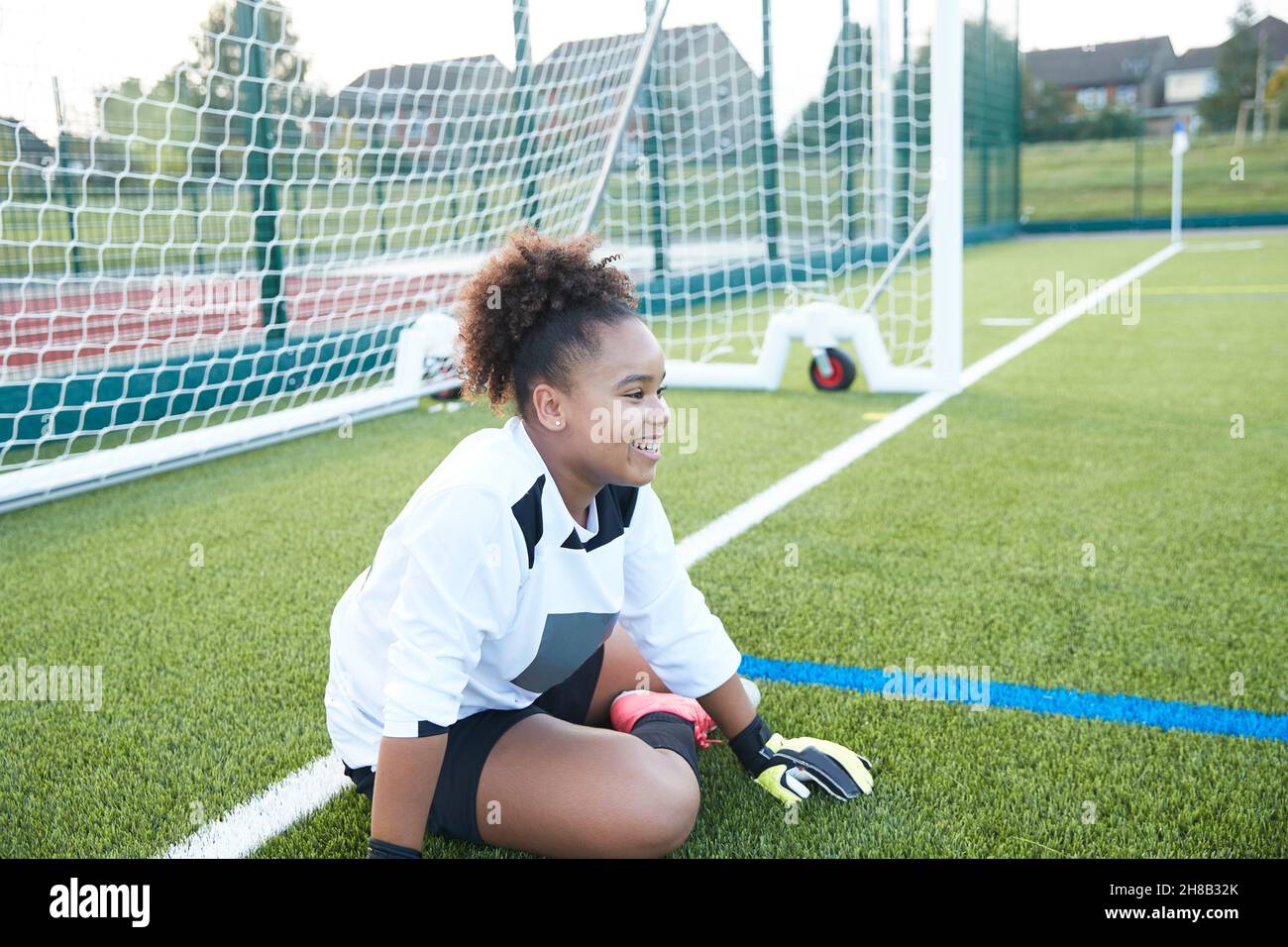UK, Smiling female soccer goalie sitting near goal Stock Photo - Alamy