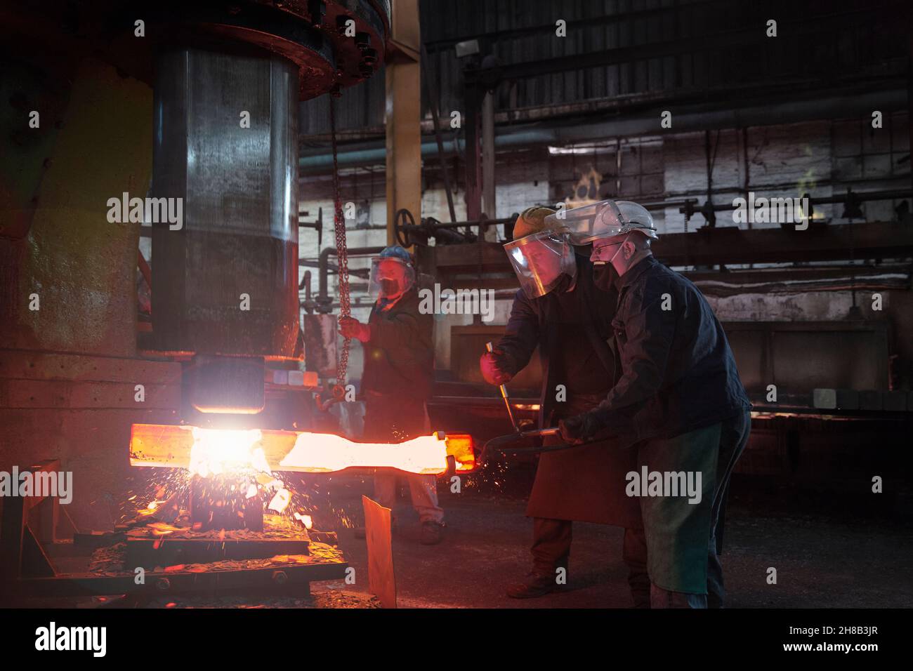 Forge workers pre form red hot steel billet Stock Photo - Alamy