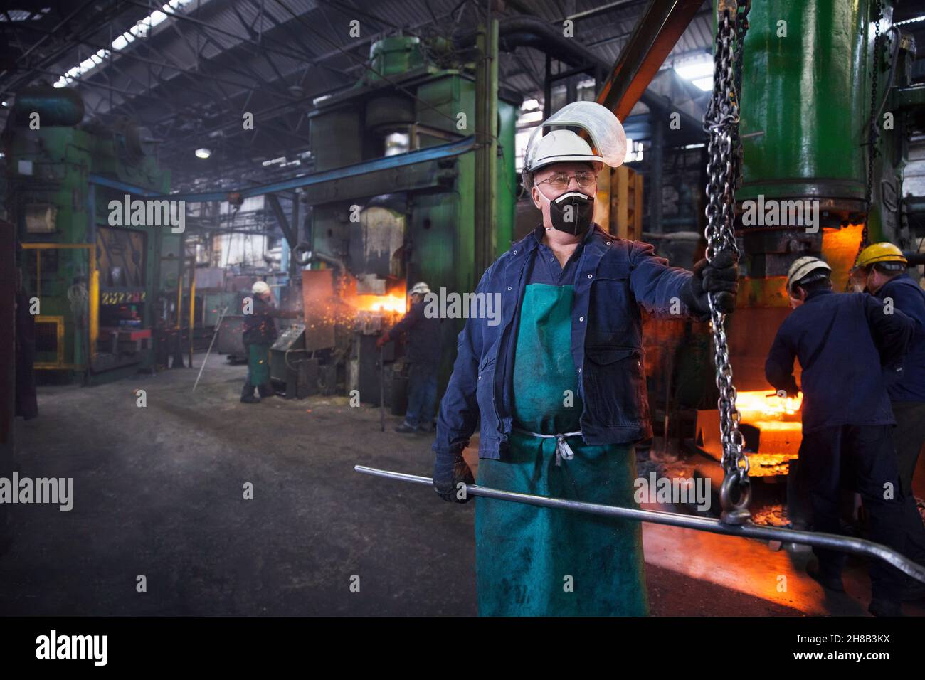 Operative prepares to hook steel billet out of furnace. Team in ...