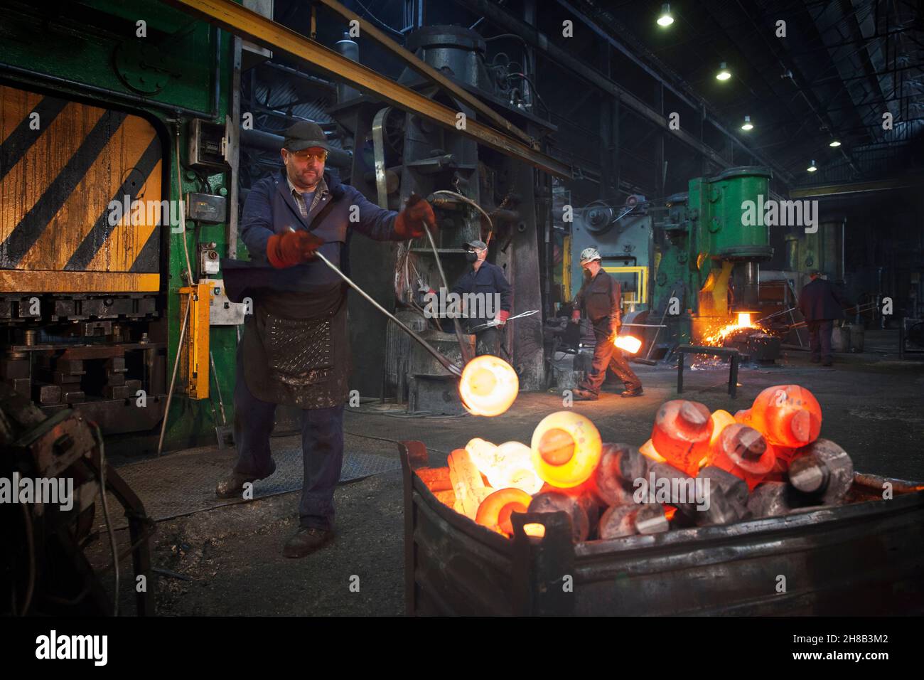 Forge worker swings finished forged component Stock Photo - Alamy