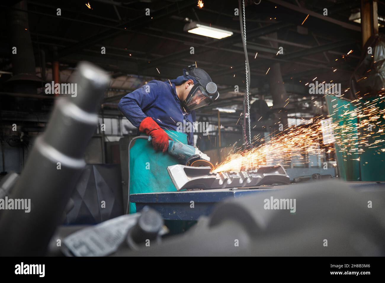 Forge worker grinding (or linishing) flight bar (mining component ...