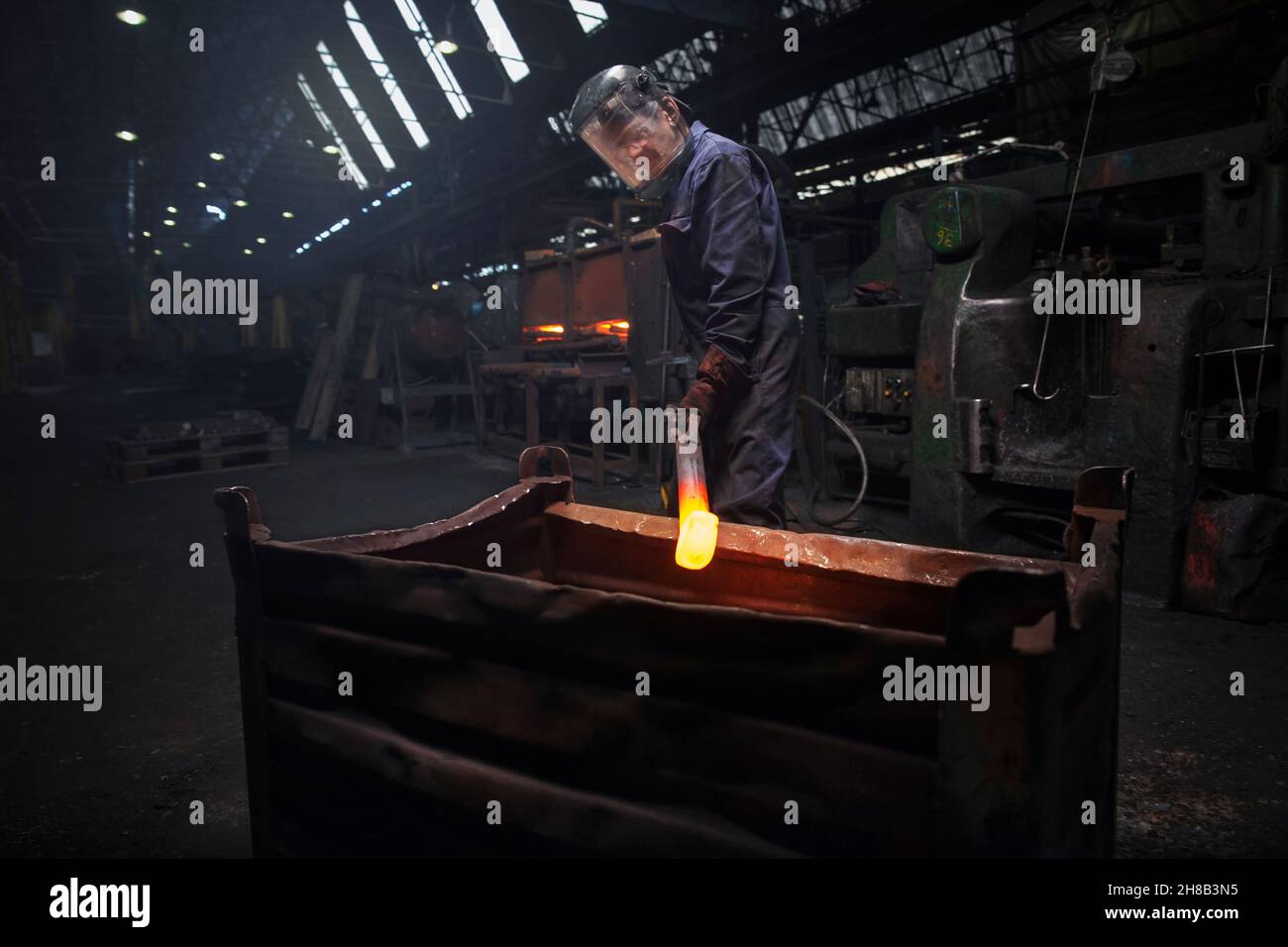 Forge worker preparing to release finished upset forging into steel ...