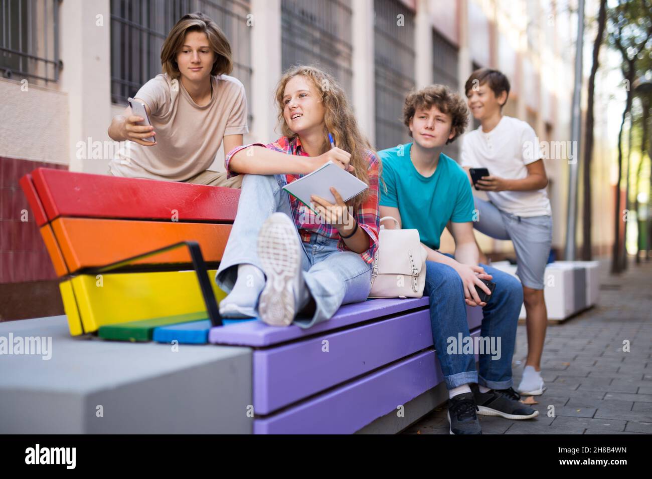 Schoolchildren sitting on bench in schoolyard Stock Photo - Alamy