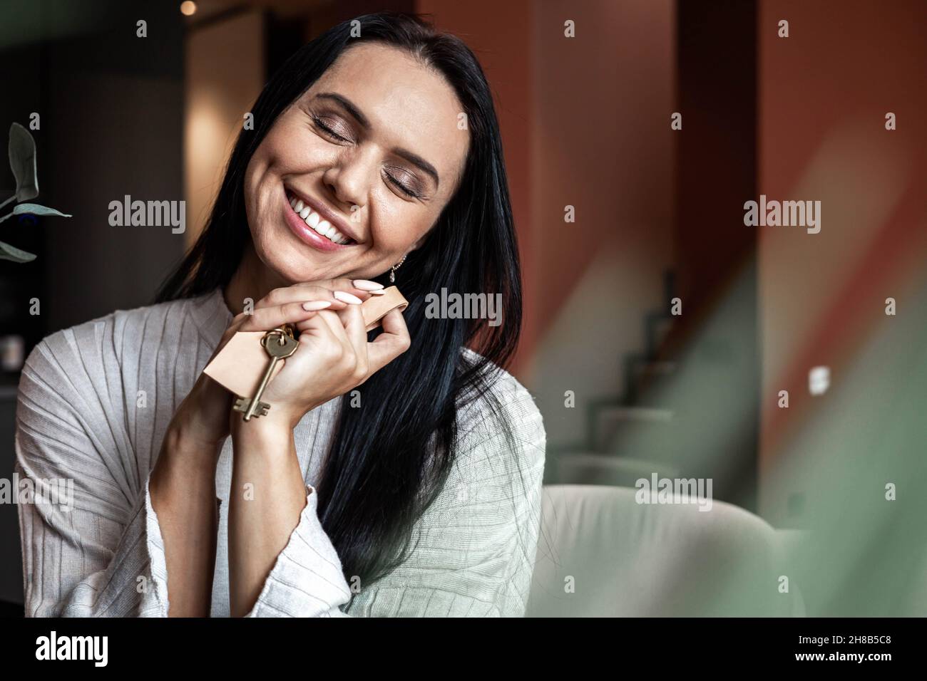 Laughing young brunette woman holding keys from new flat or house ...