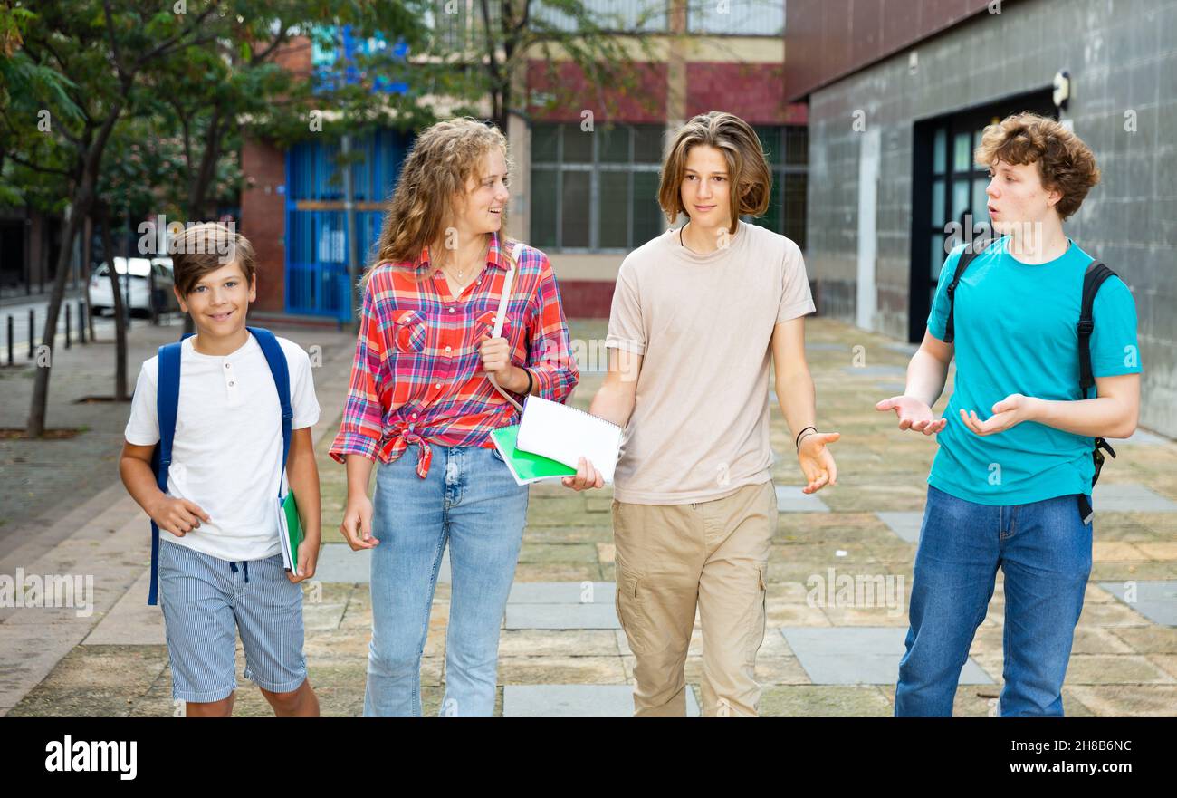 Group of positive cheerful teenagers hanging out on streets of city on ...