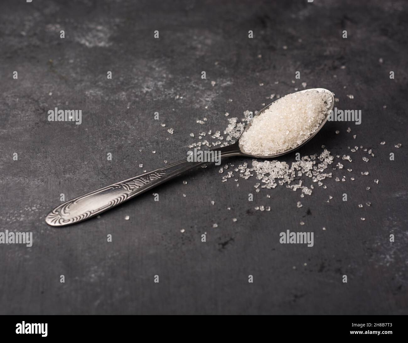 granulated white sugar, also called table sugar in a spoon, rustic dark ...
