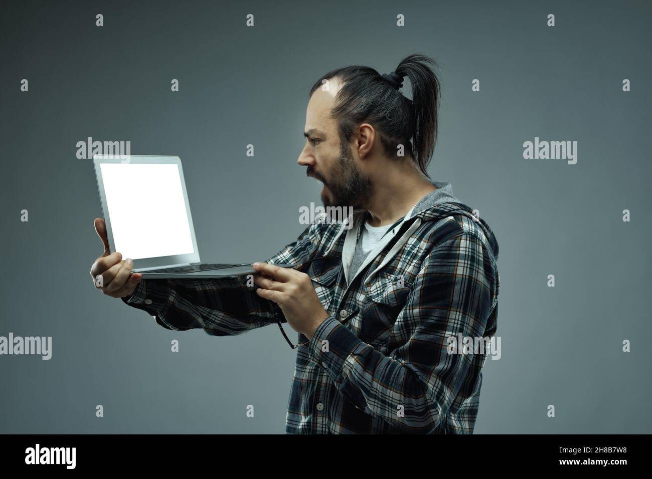 Distraught man staring at his blank handheld laptop screen in horror ...