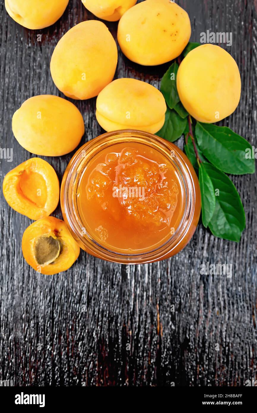 Jam apricot in glass jar, fruits and a branch with green leaves on ...