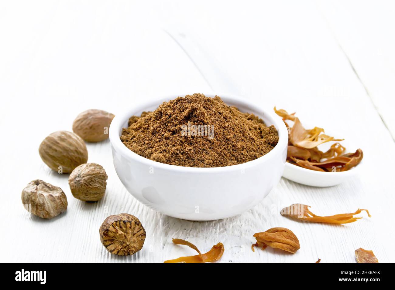 Ground nutmeg in a bowl and dried nutmeg arillus in a spoon, whole nuts ...