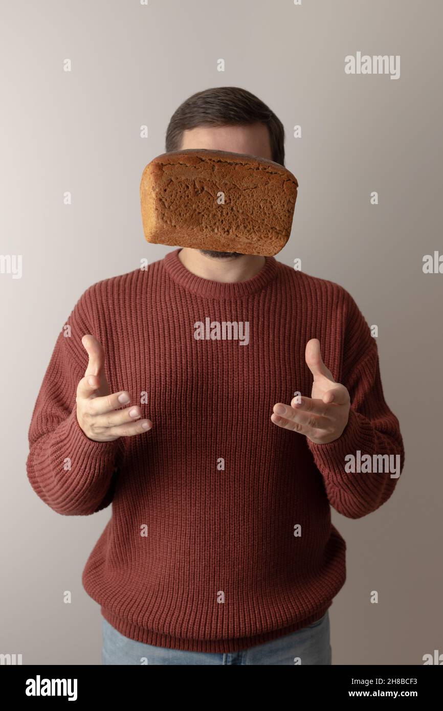 A man in a sweater throw up a loaf of rye bread into the air. Front ...