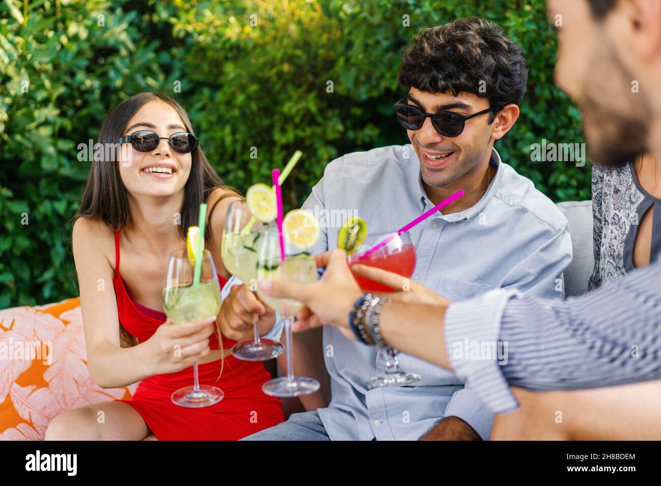 Happy friends having fun toasting tropical fruit cocktails sitting on a ...