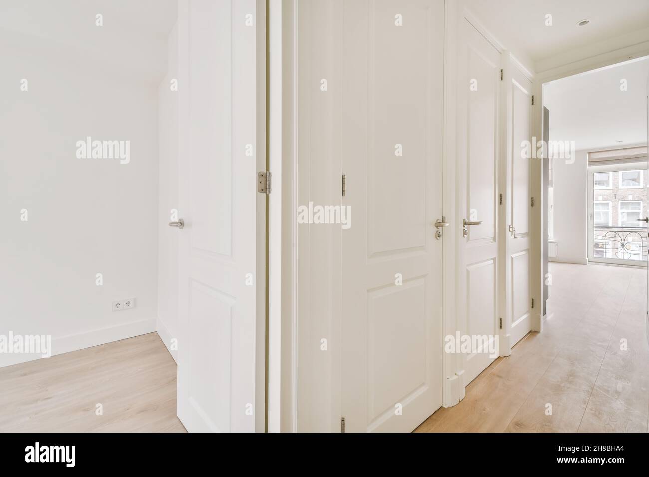 A perspective view of an empty narrow hallway with white walls and ...