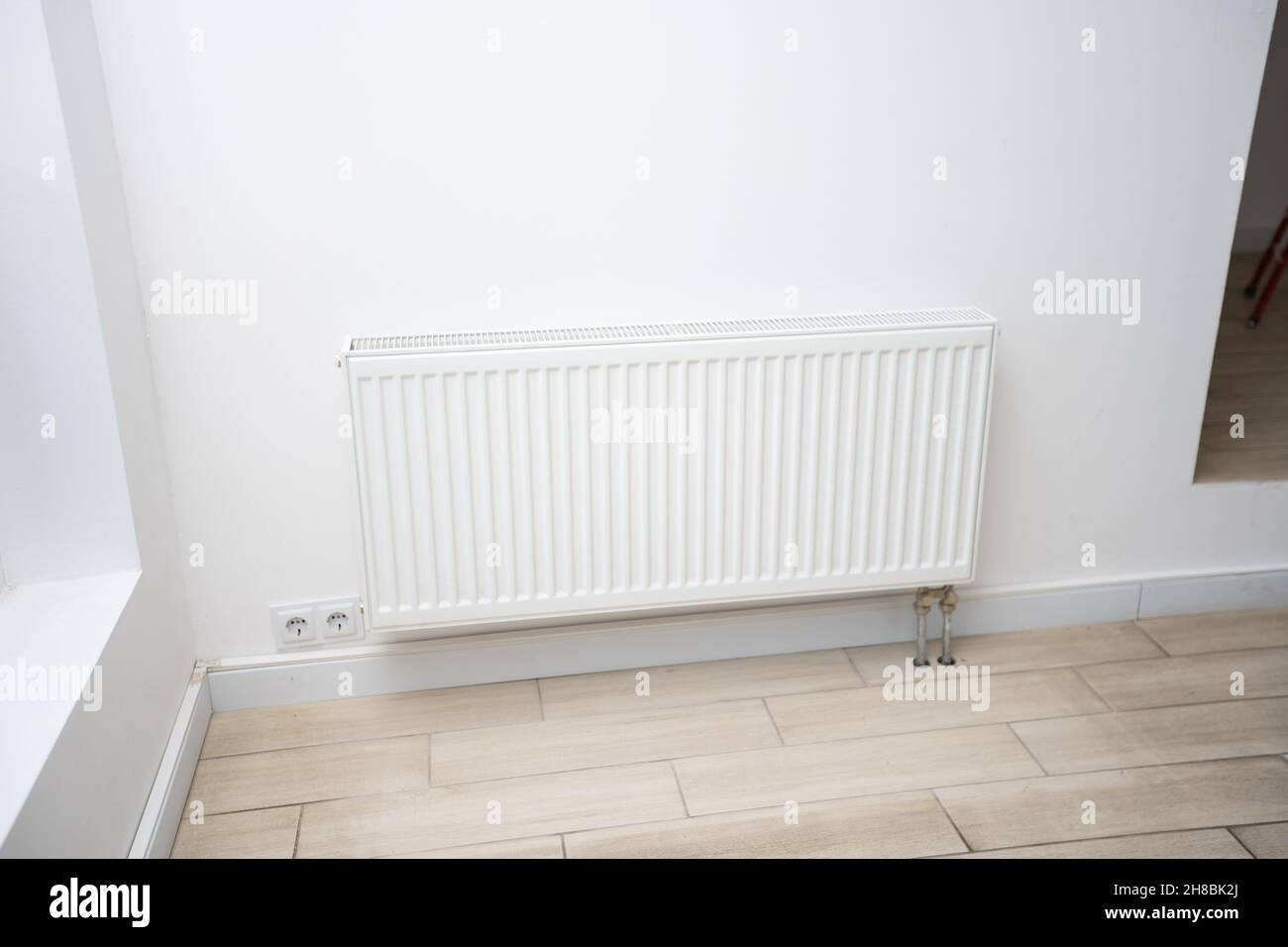 Heating radiator in a white room with laminated wooden floor Stock ...