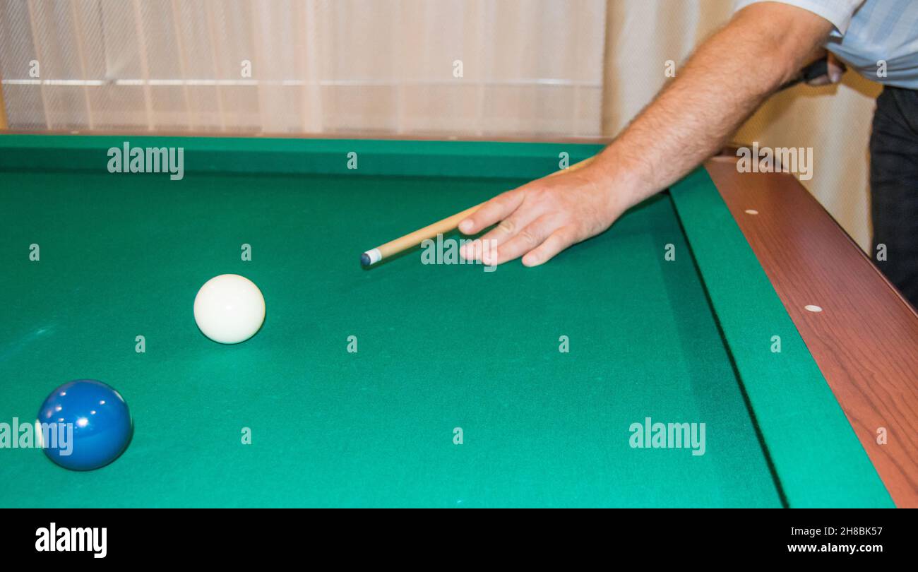 A close-up of a billiard table with balls pointing the athlete's hands ...