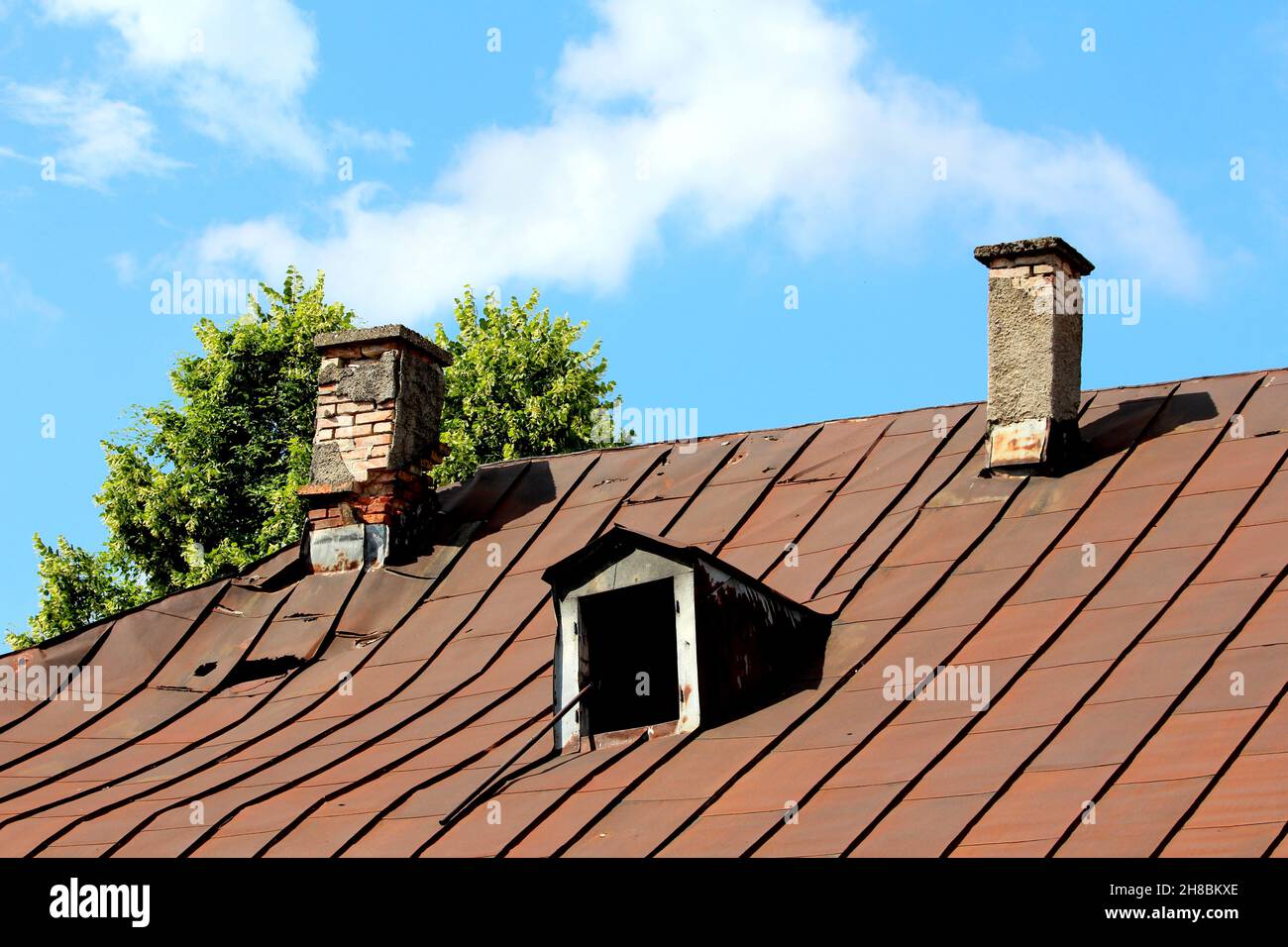 Damaged partially broken old roof window frame without glass on top of abandoned suburban family ...