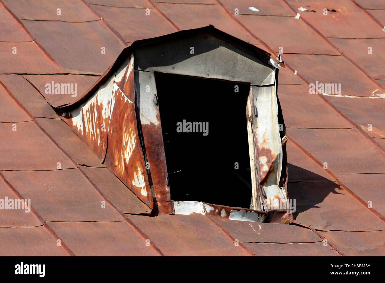Severely damaged cracked and partially broken old roof window frame without glass on top of ...