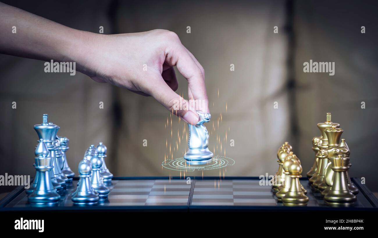 Hand businessman moving the golden knight chess fighting silver knight ...