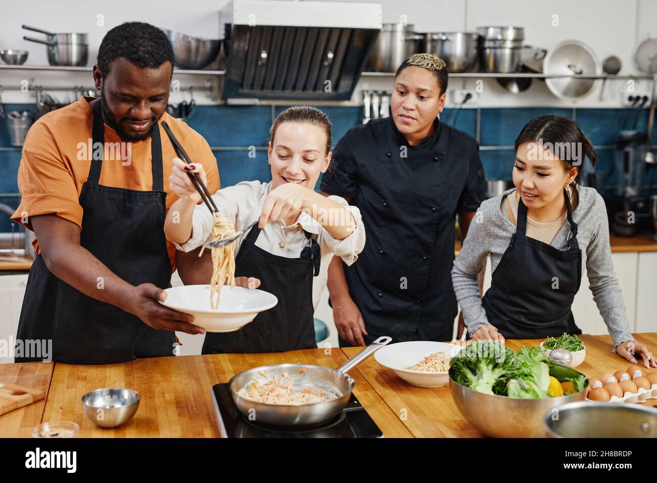 Waist up portrait of diverse group of people cooking together during ...