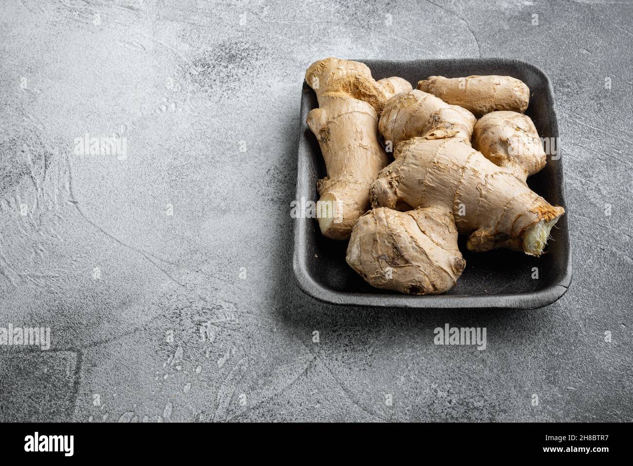Fresh ginger root set, in plastic market container, on gray stone ...