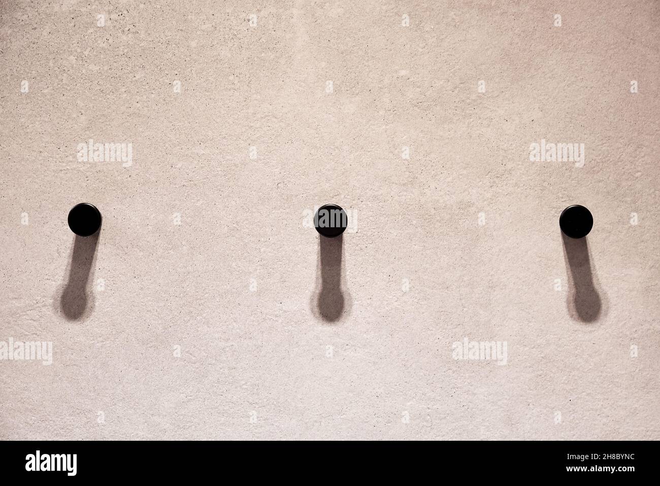 Three metallic black hooks on the empty wall in the modern wardrobe ...