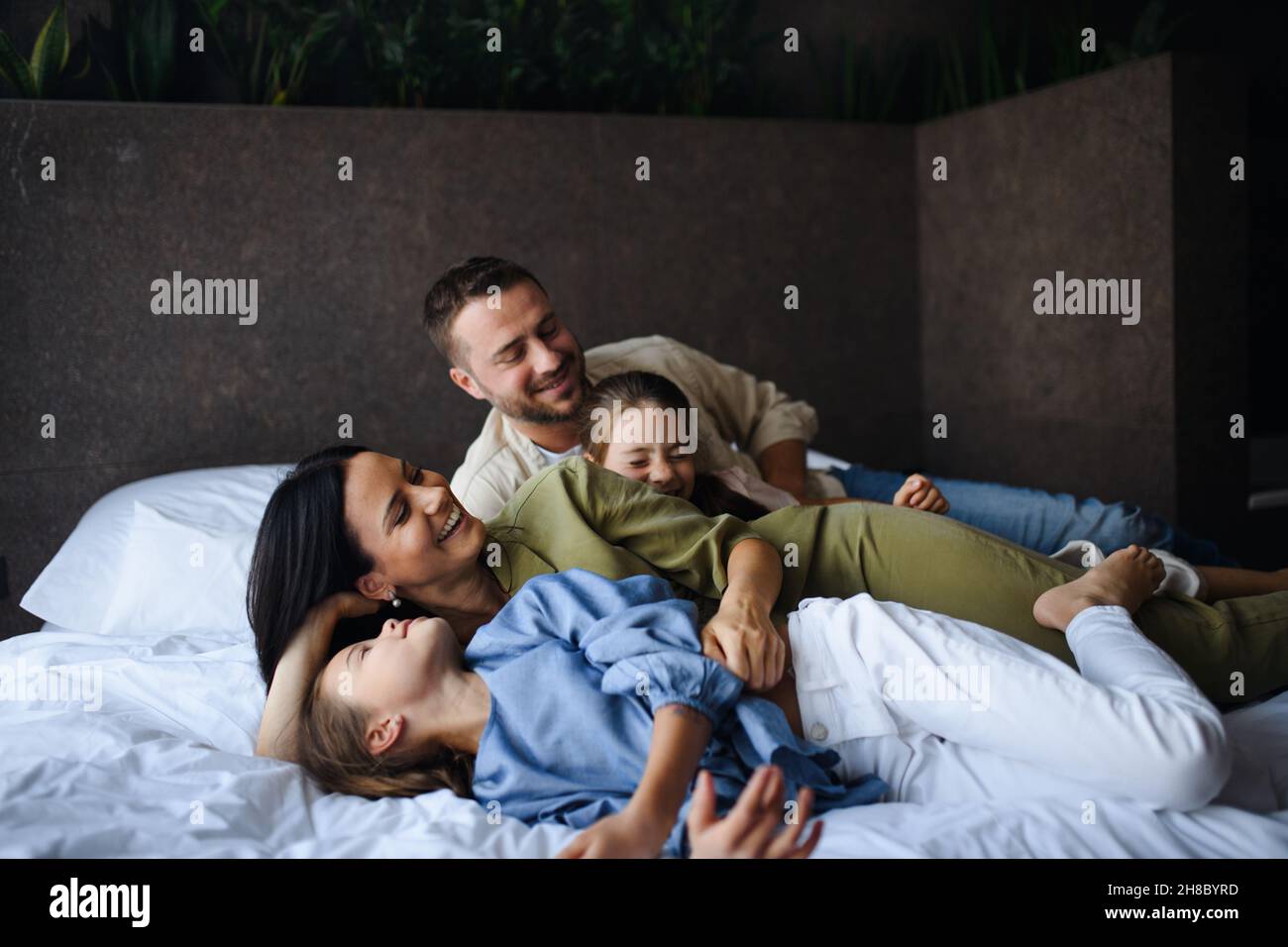 Happy young family with two children lying on bed at hotel, summer ...