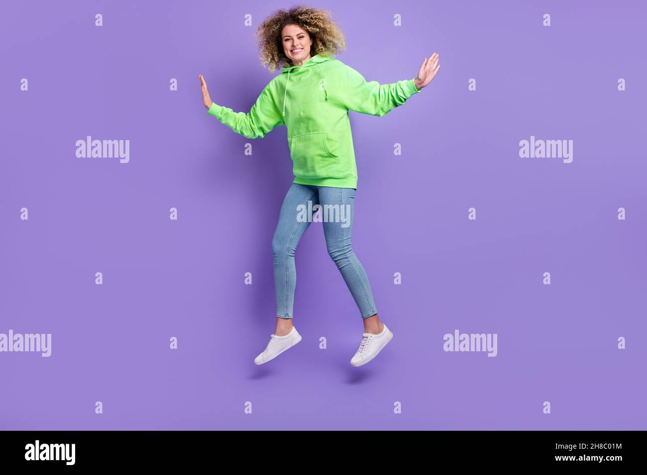 Photo of adorable girl wear green sweatshirt arms sides jumping high ...