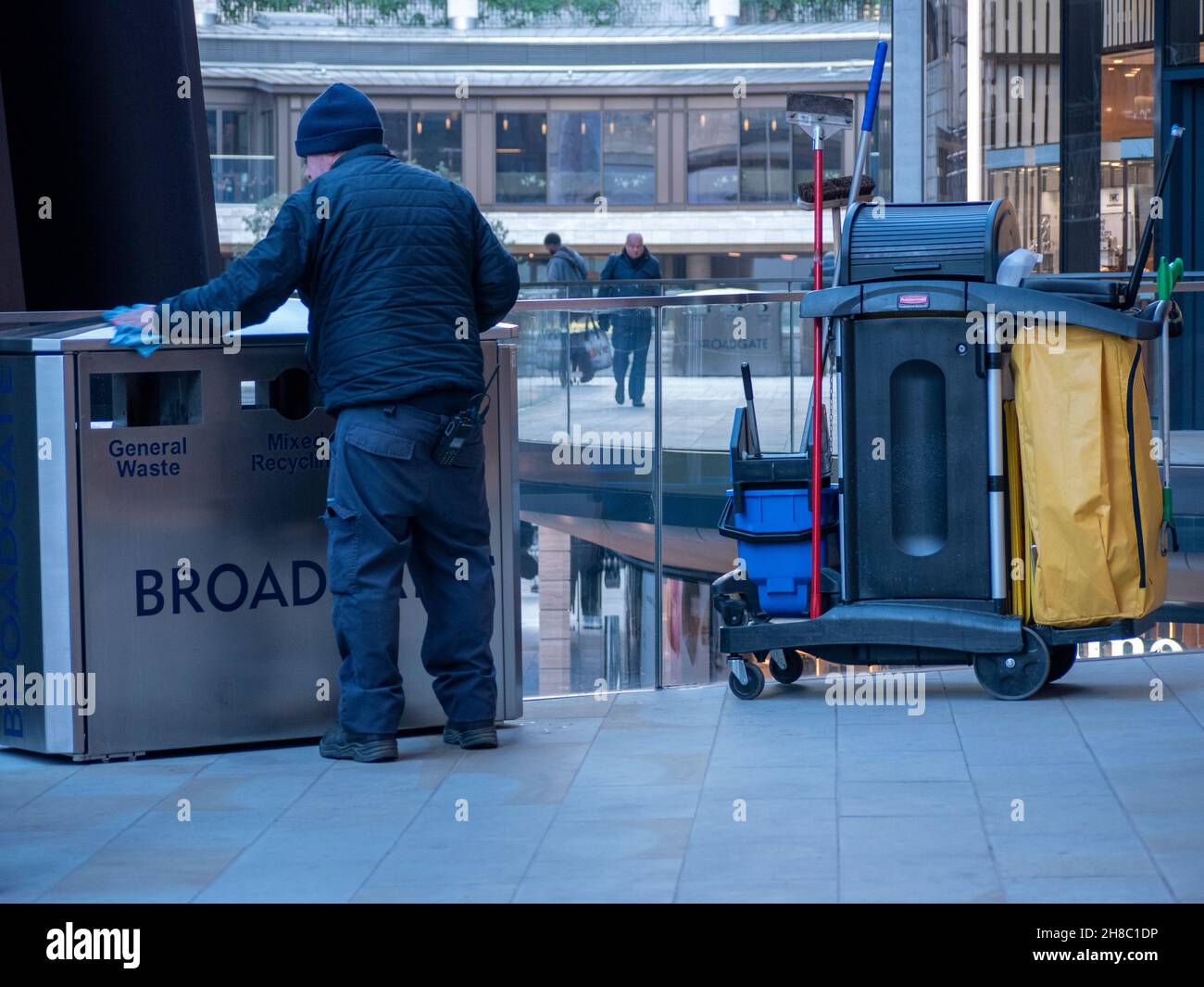 Cleaner polishing waste bins in Broadgate, London. Broadgate is an ...