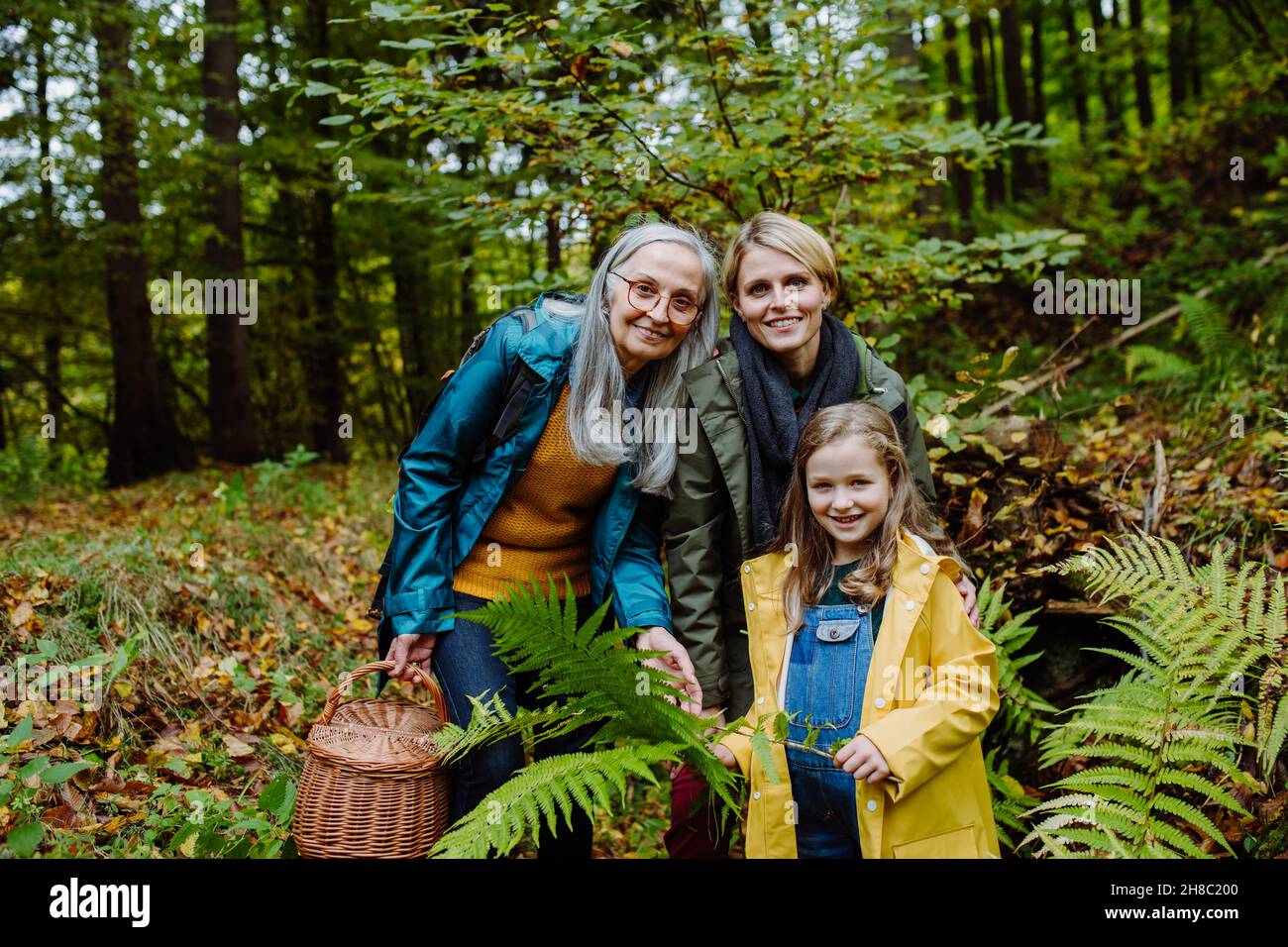 Small girl with mother and grandmother on walk outoors in forest ...