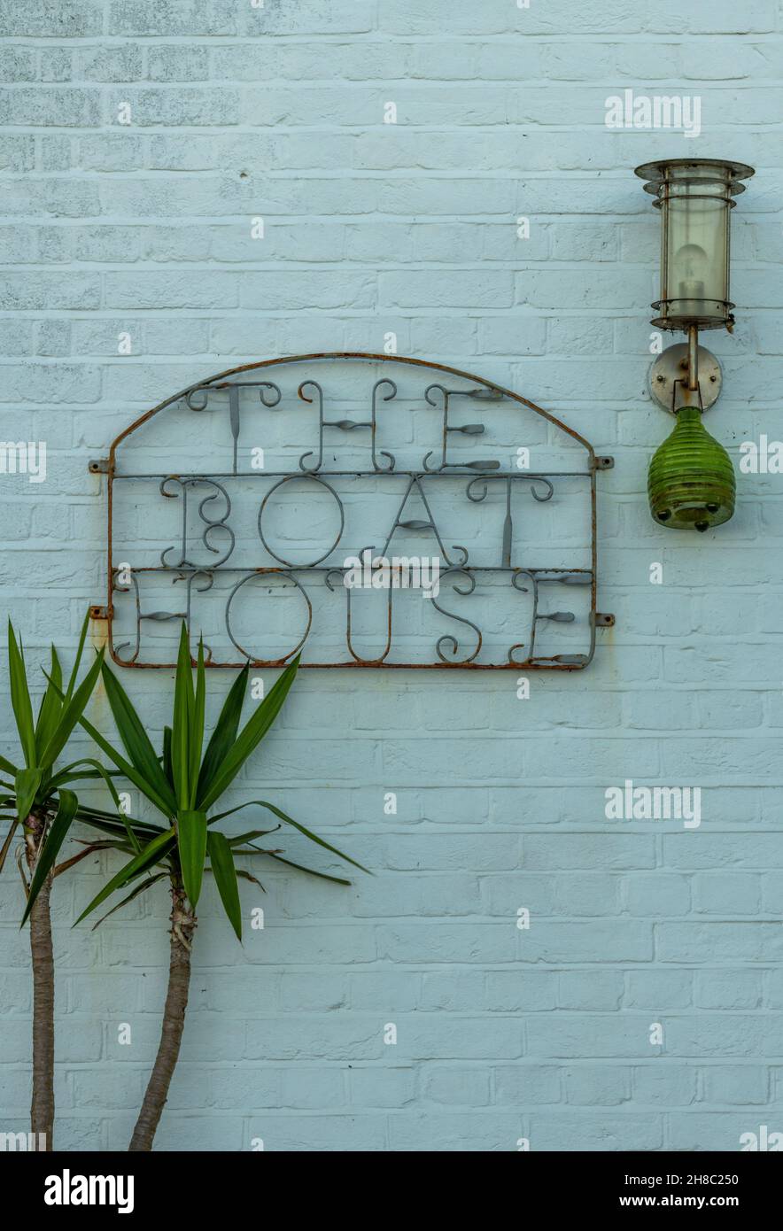 the boat house sign on a seaside restaurant with old lantern and plants ...