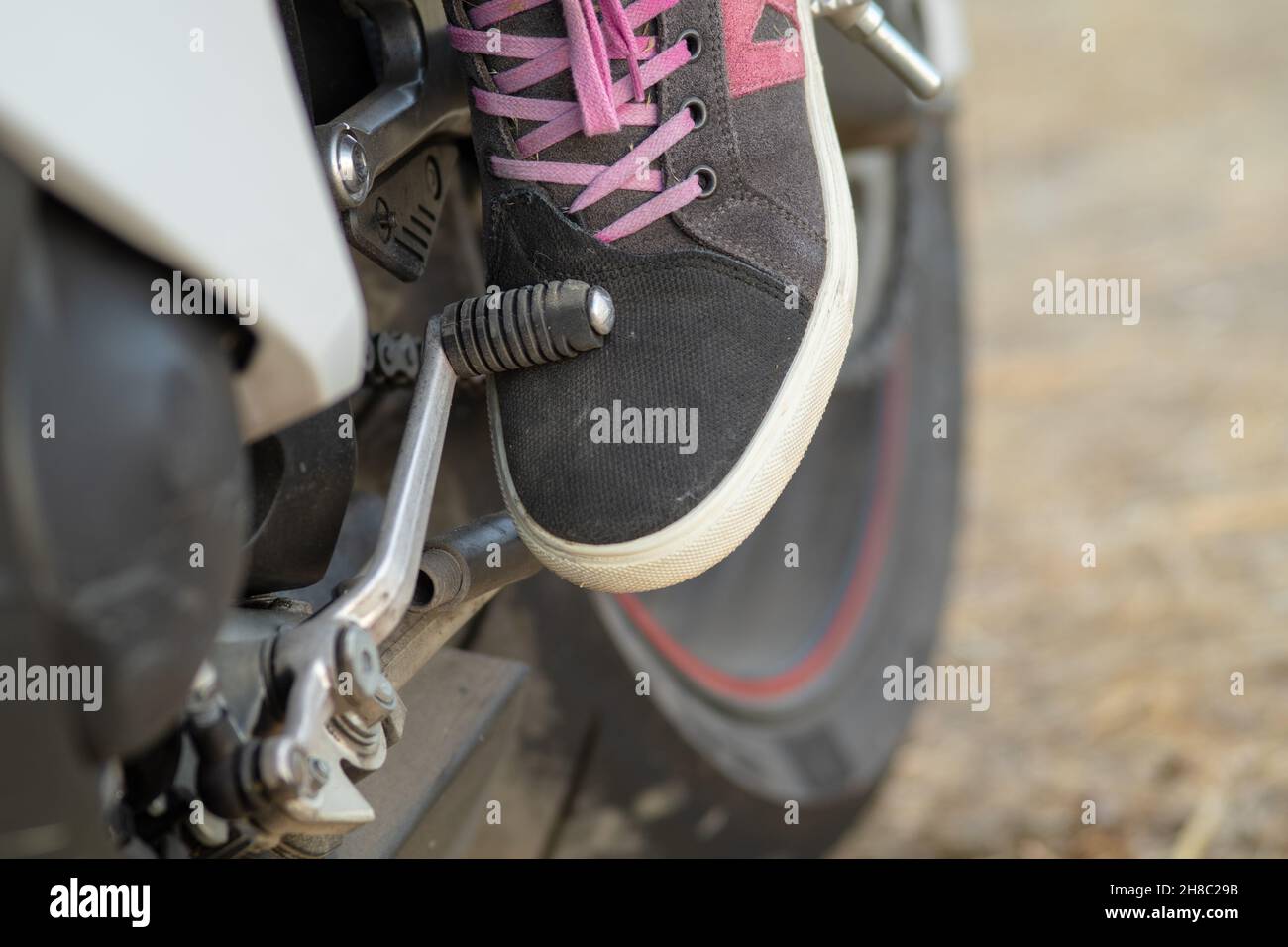 detail of the left foot of a motorcyclist wearing safety shoe with pink ...