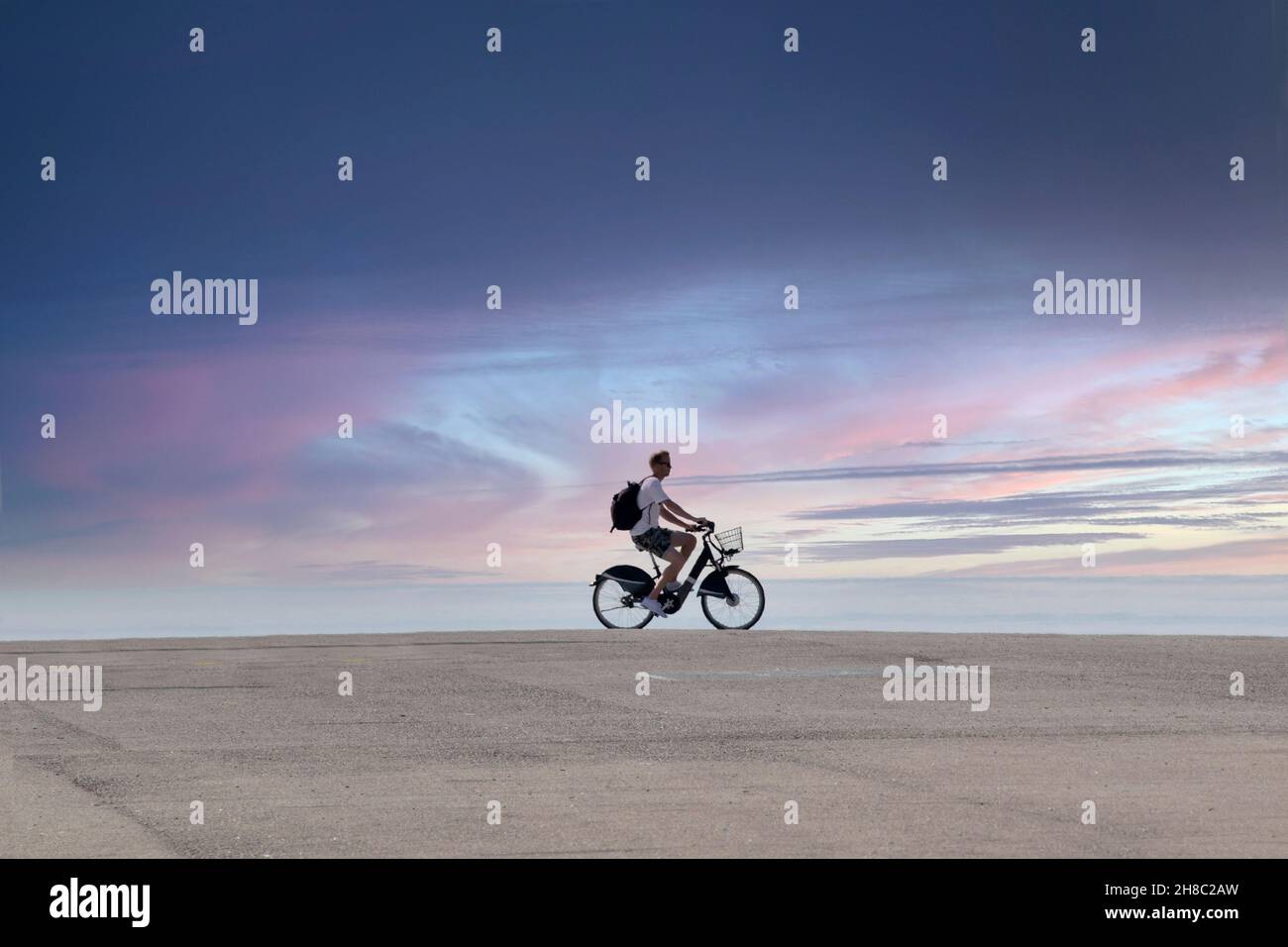 Isolated man riding a bicycle against a sunset sky. Negative space ...