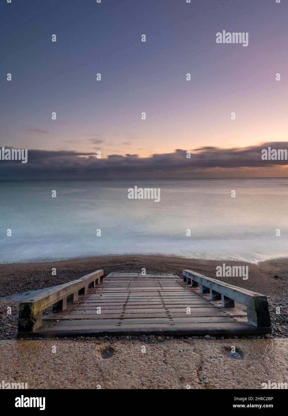 old wooden jetty on beach in atmospheric moody light on coastline of ...