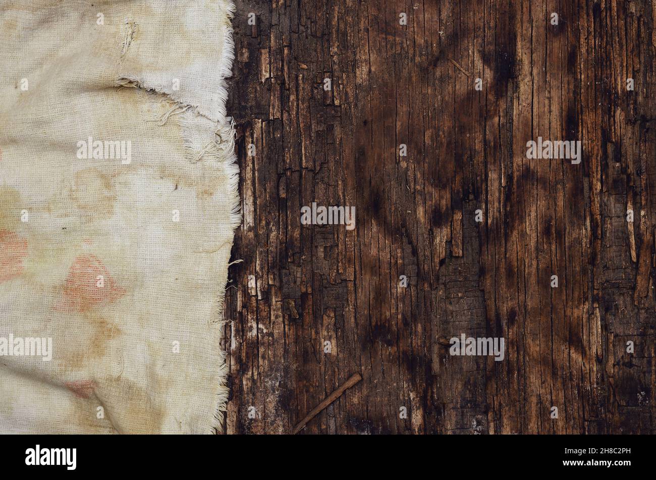 Torn rag on an old burnt wooden surface. Dirty cloth on the left side ...