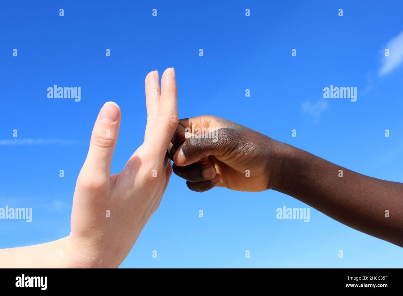 a white-skinned hand and a black-skinned hand high-five each other in ...