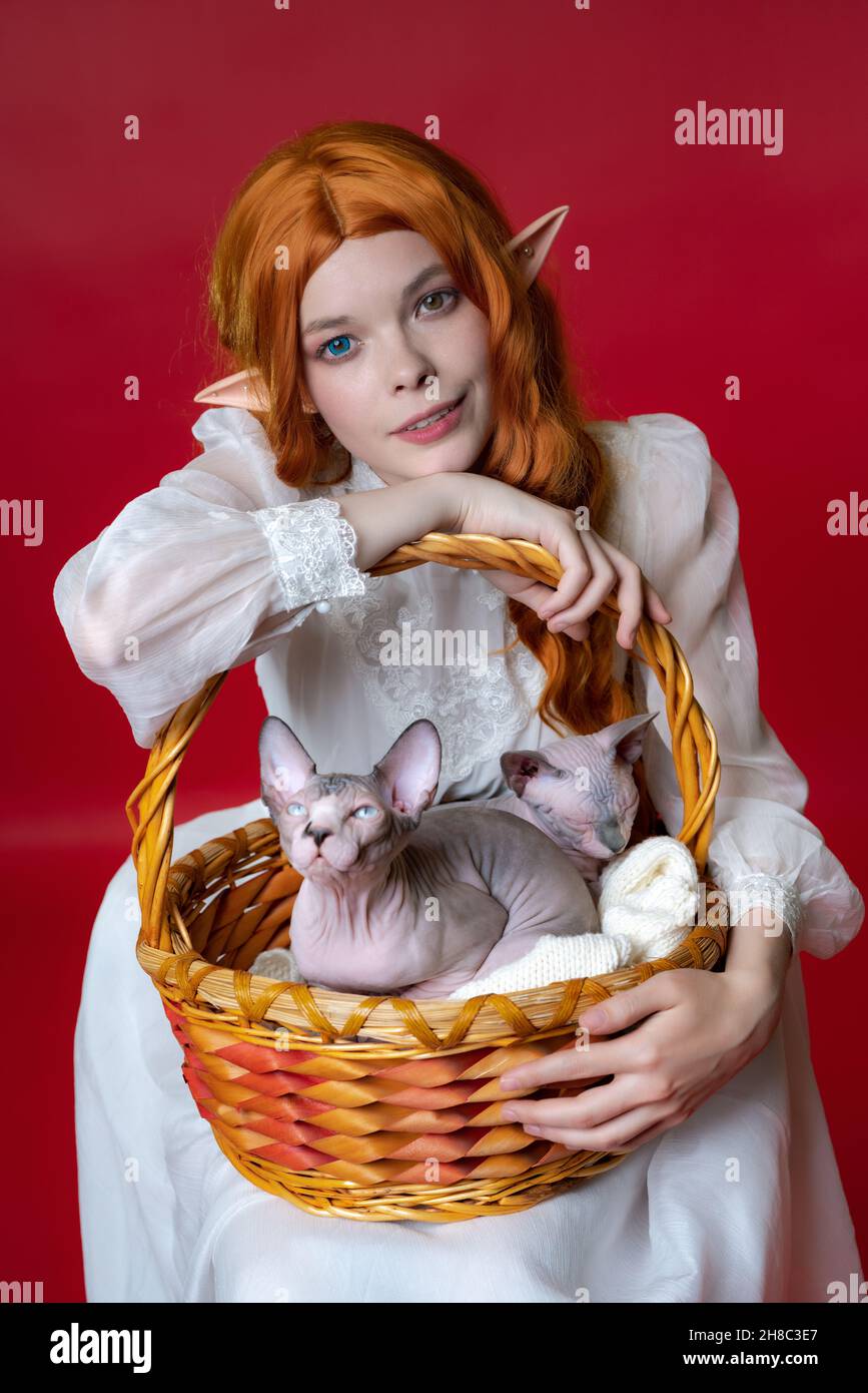 Cosplayer elf young redhead woman smiles, leaning on brown basket in ...
