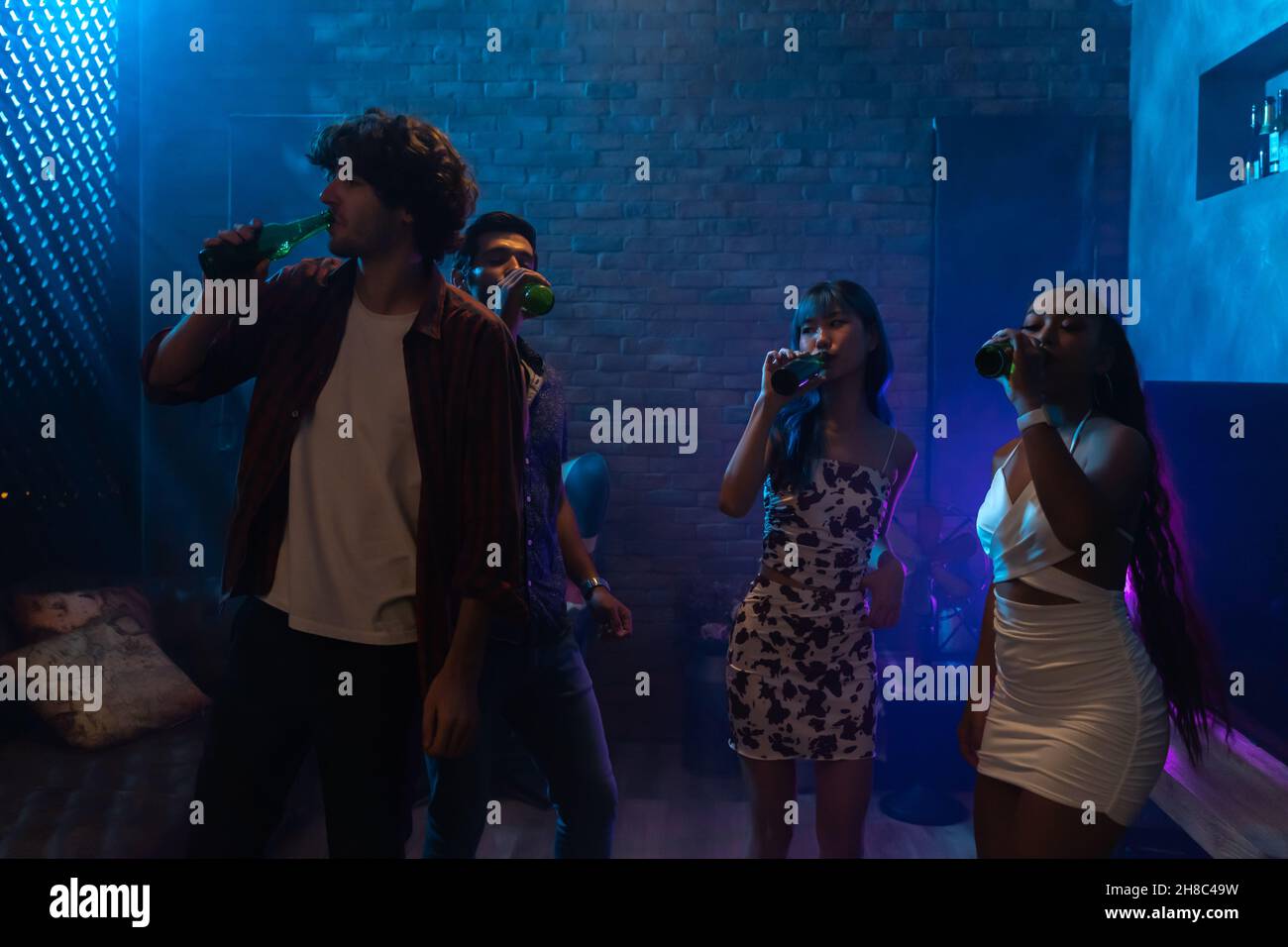 Diverse group of young people partying and toasting a drink at the ...