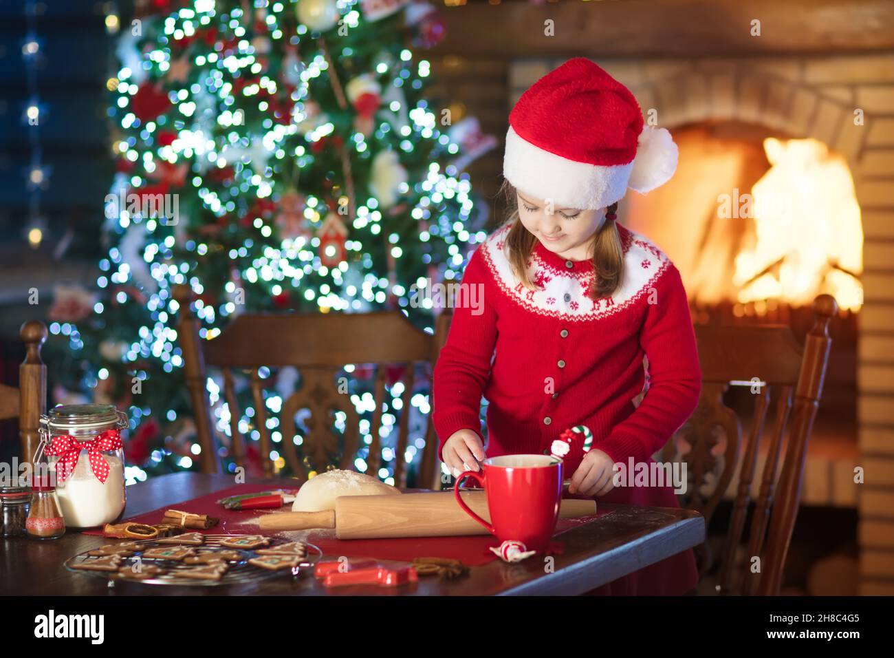Child baking Christmas cookies at fire place and decorated tree. Kids ...