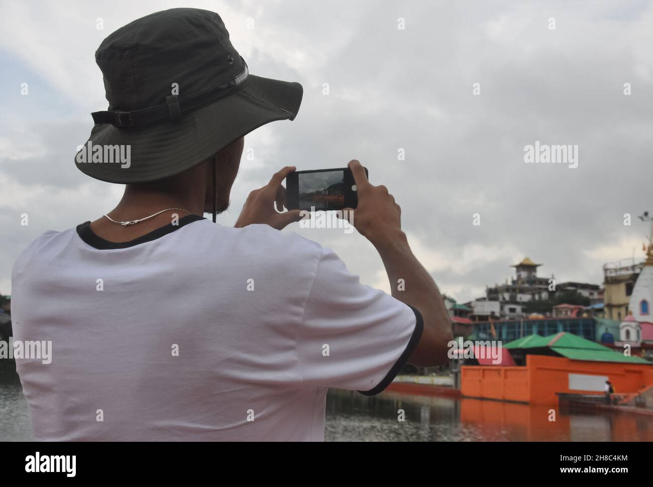 Back view of a male tourist taking photo of landscape with smartphone ...