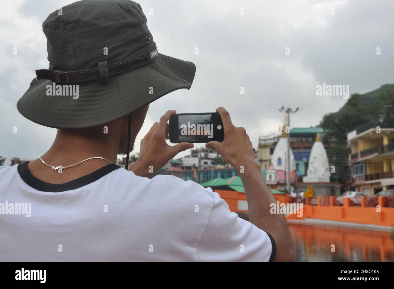 Back view of a male tourist taking photo of landscape with smartphone ...