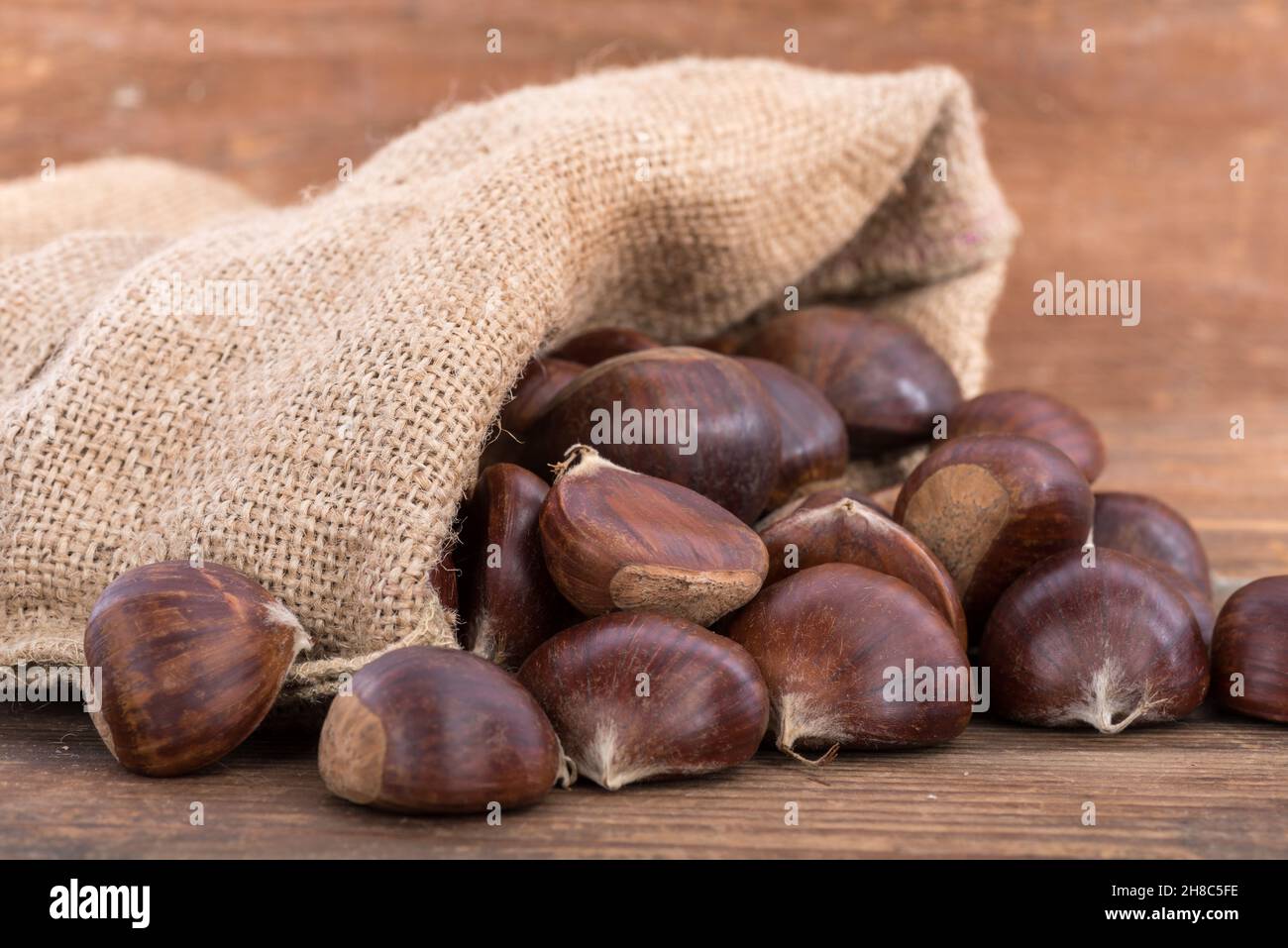 Raw chestnuts with burlap on wooden background Stock Photo - Alamy