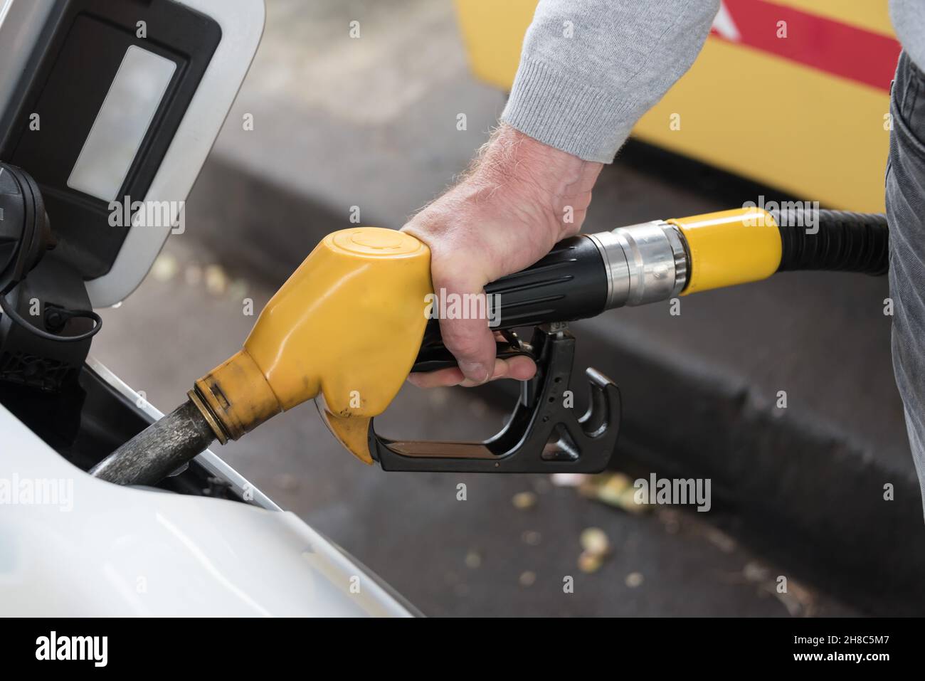 Hand holding yellow fuel pump nozzle and refilling car Stock Photo - Alamy